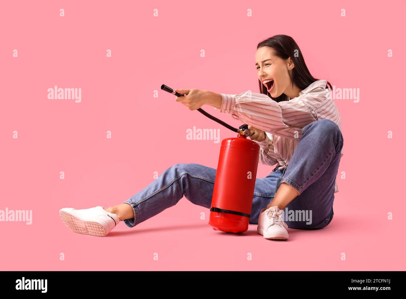 Scared young woman with fire extinguisher on pink background Stock ...