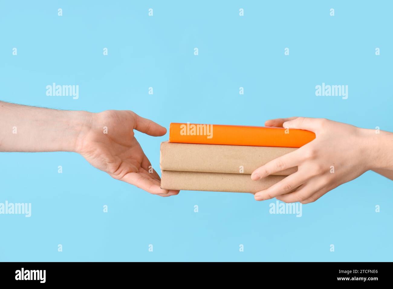 Hand passing stack of books to another person on pink background Stock ...