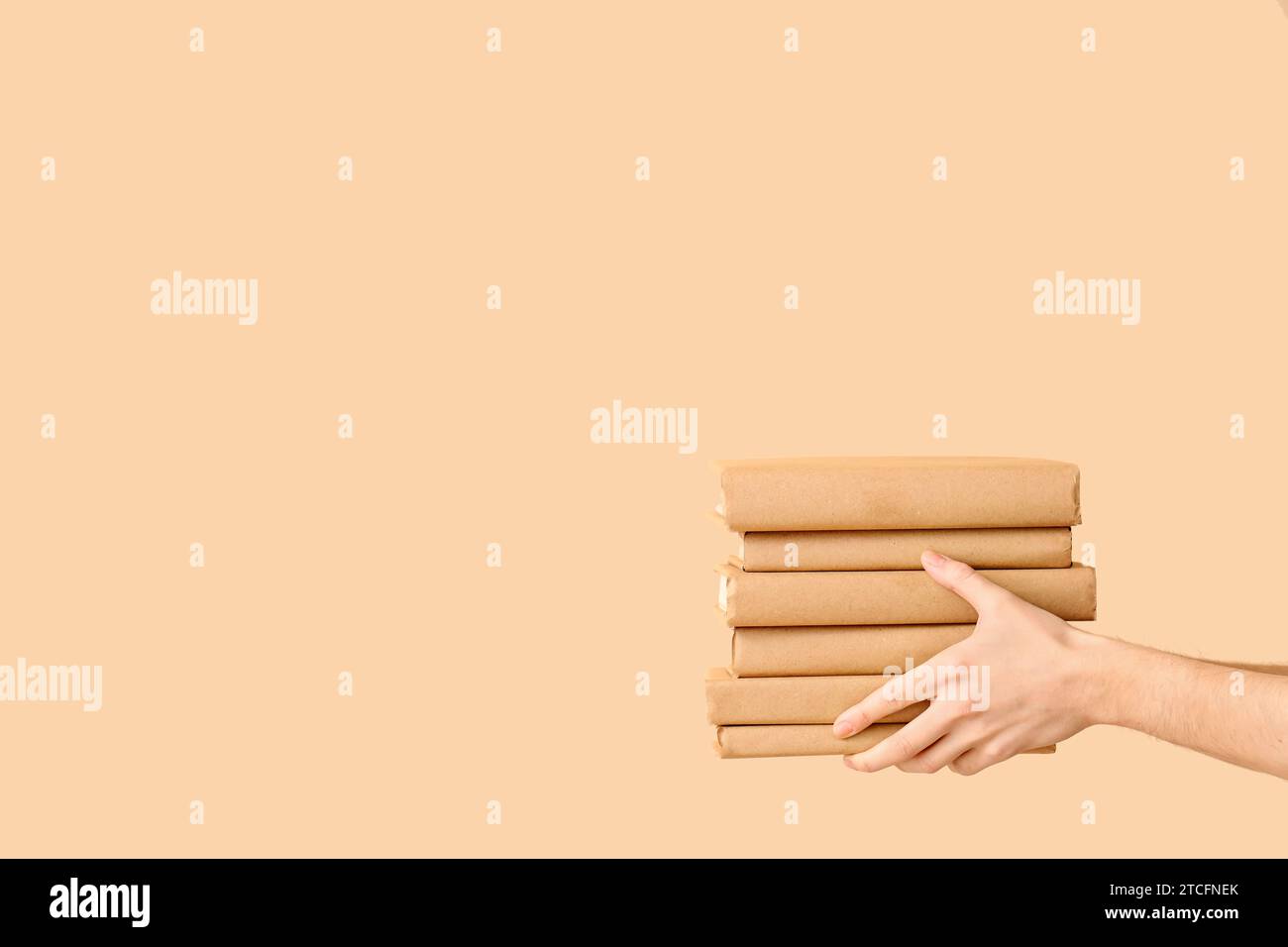 Hands holding stack of books on beige background Stock Photo - Alamy