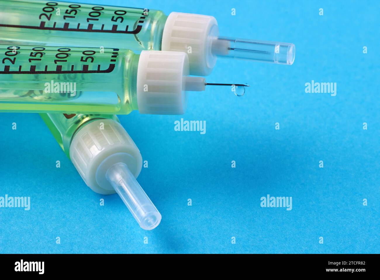 Three syringes with a drop of medicine close-up in a stack on a blue ...