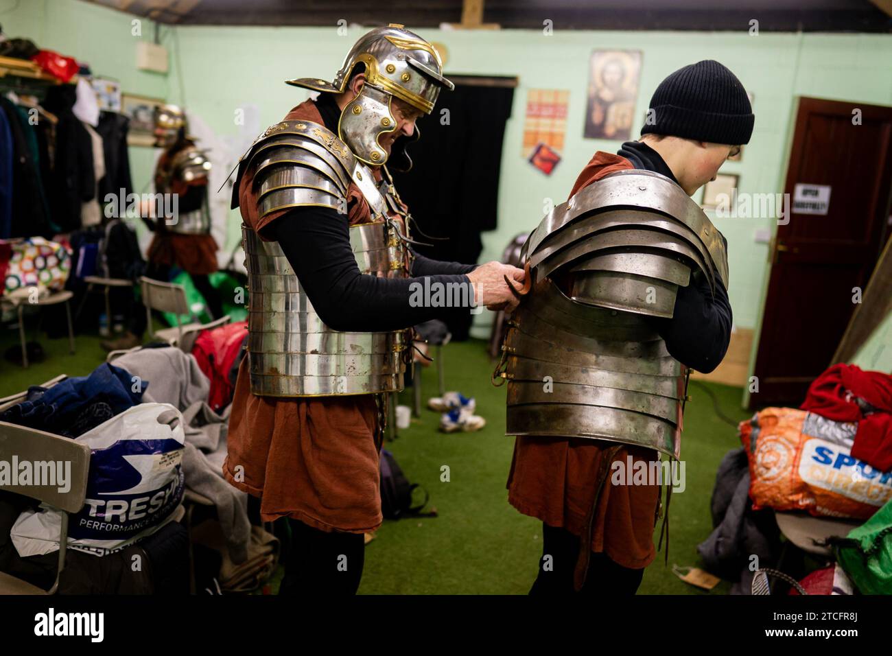 Actors playing soldiers help each other into costume before the dress ...