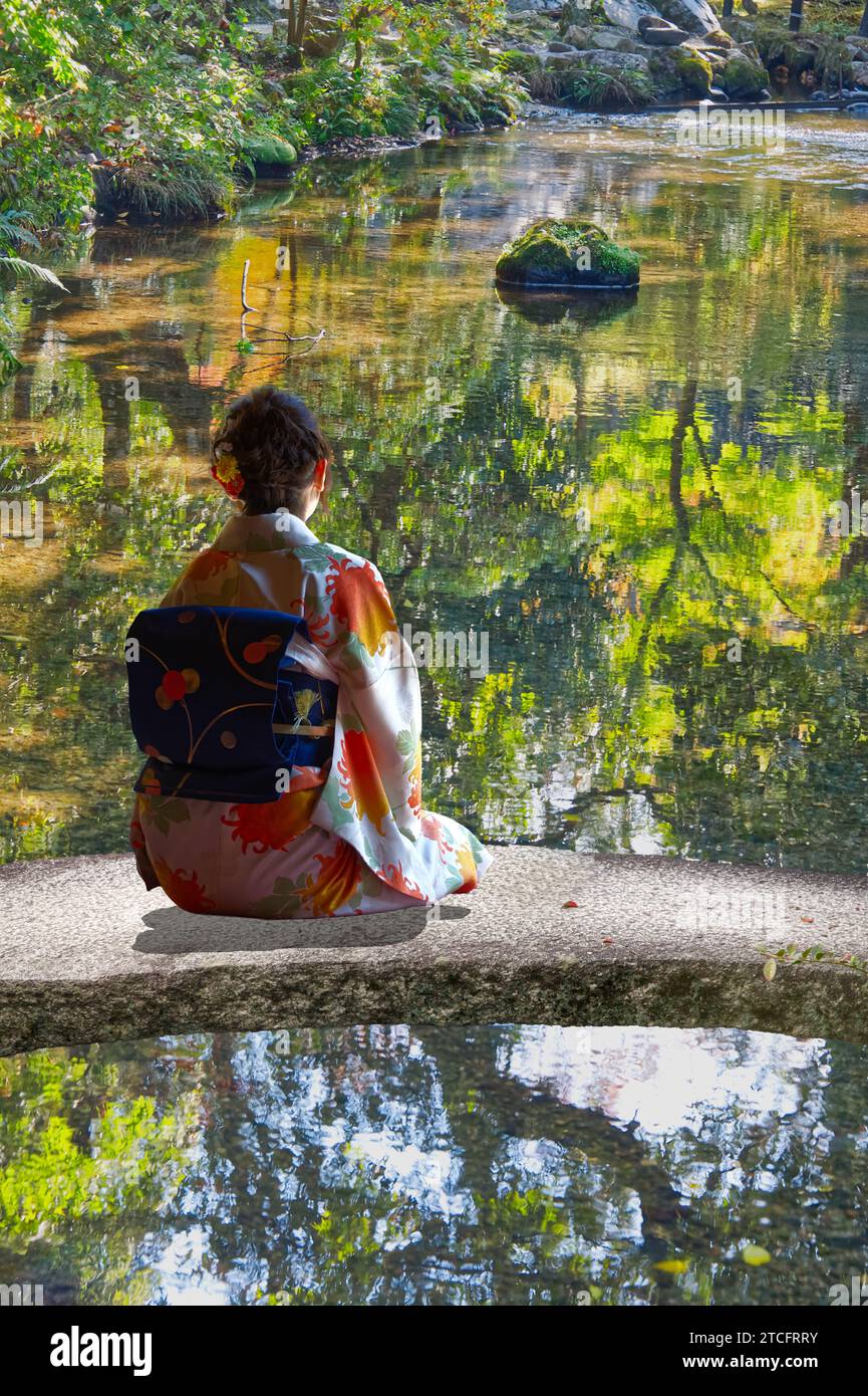 A Japanese young adult woman in kimono in a japanese garden sitting ...