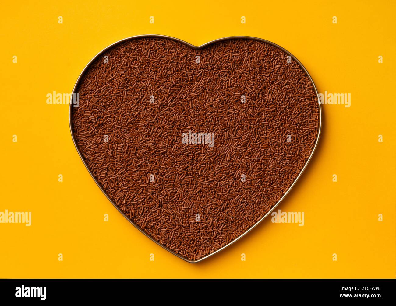 Heart-shaped box filled with chocolate chips, top view, yellow ...