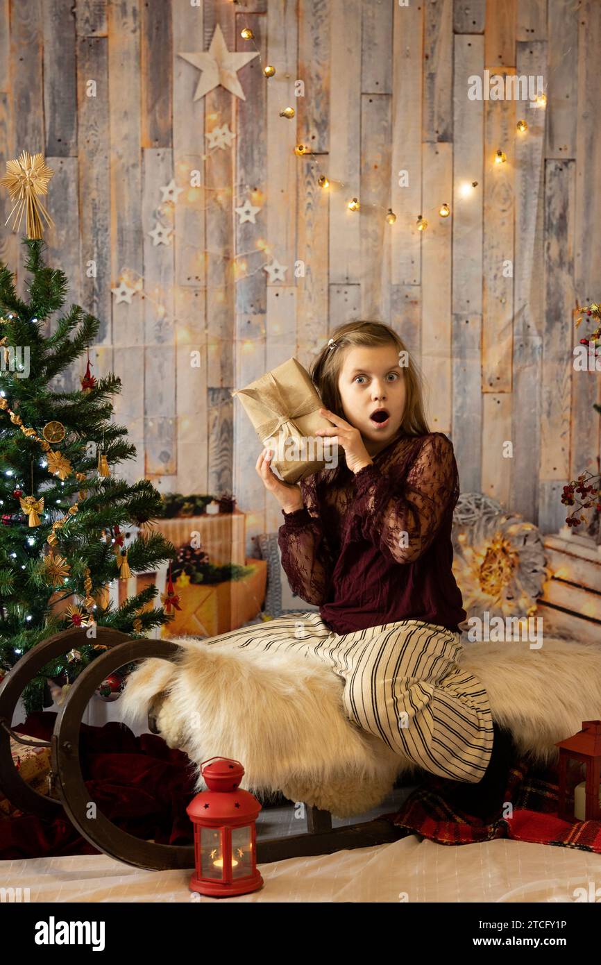 Christmas portrait of a blond girl kid on the sledges in the studio ...