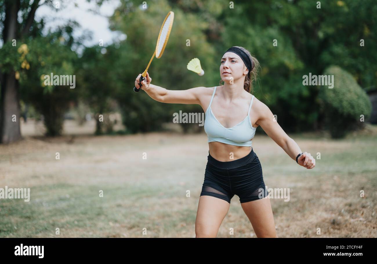 Fit and sporty girls playing badminton outdoors in a park on a sunny ...