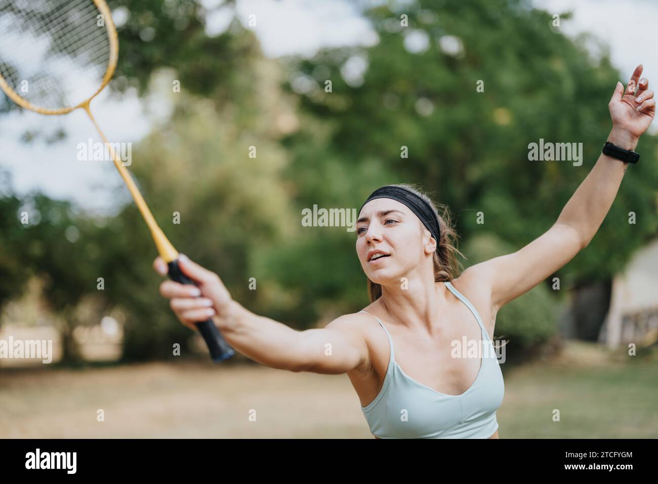 Active woman playing badminton in the park, enjoying a sunny day and ...
