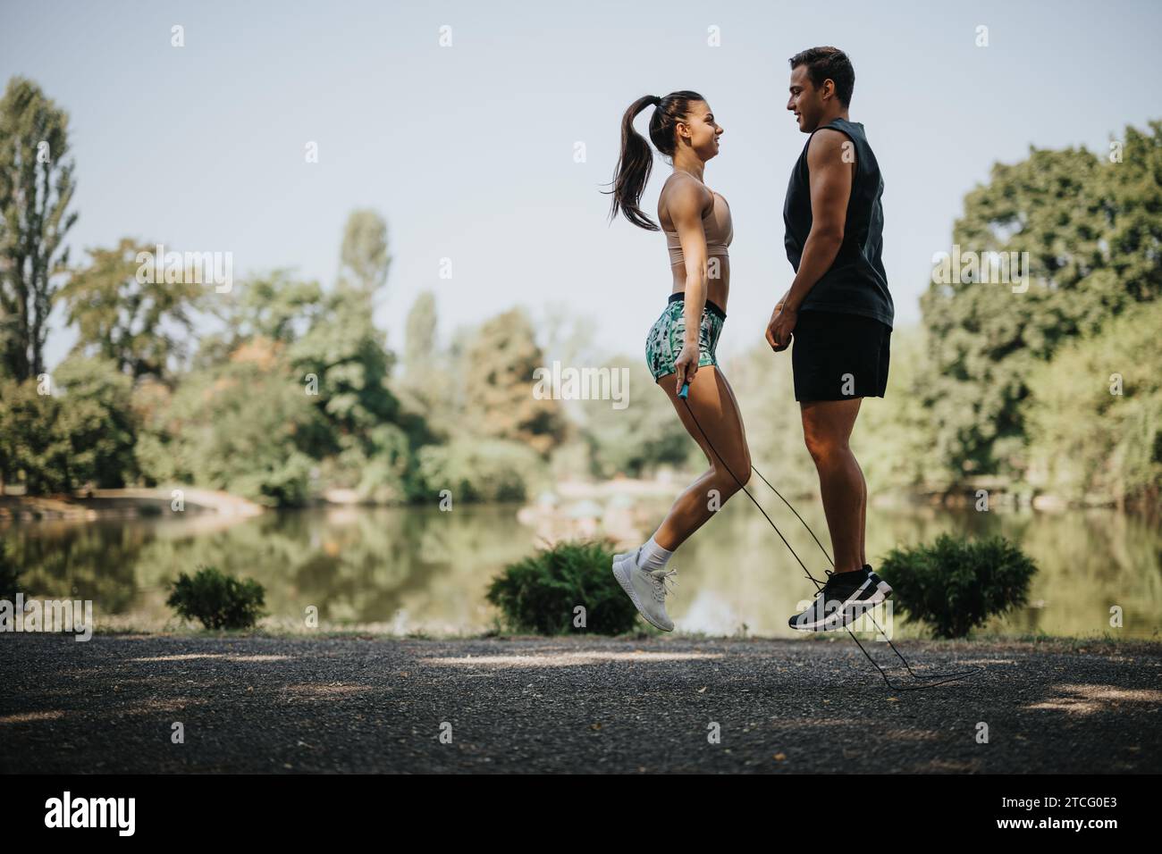 Caucasian couple jumping rope in a park. Fit bodies, sunny day, and ...