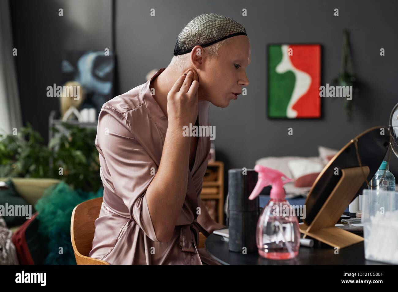 Side view portrait of adult man doing makeup at home preparing for drag ...