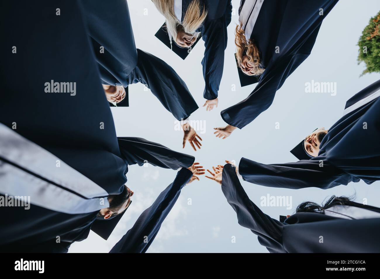 Group of graduated students putting their hands together outdoors after ...