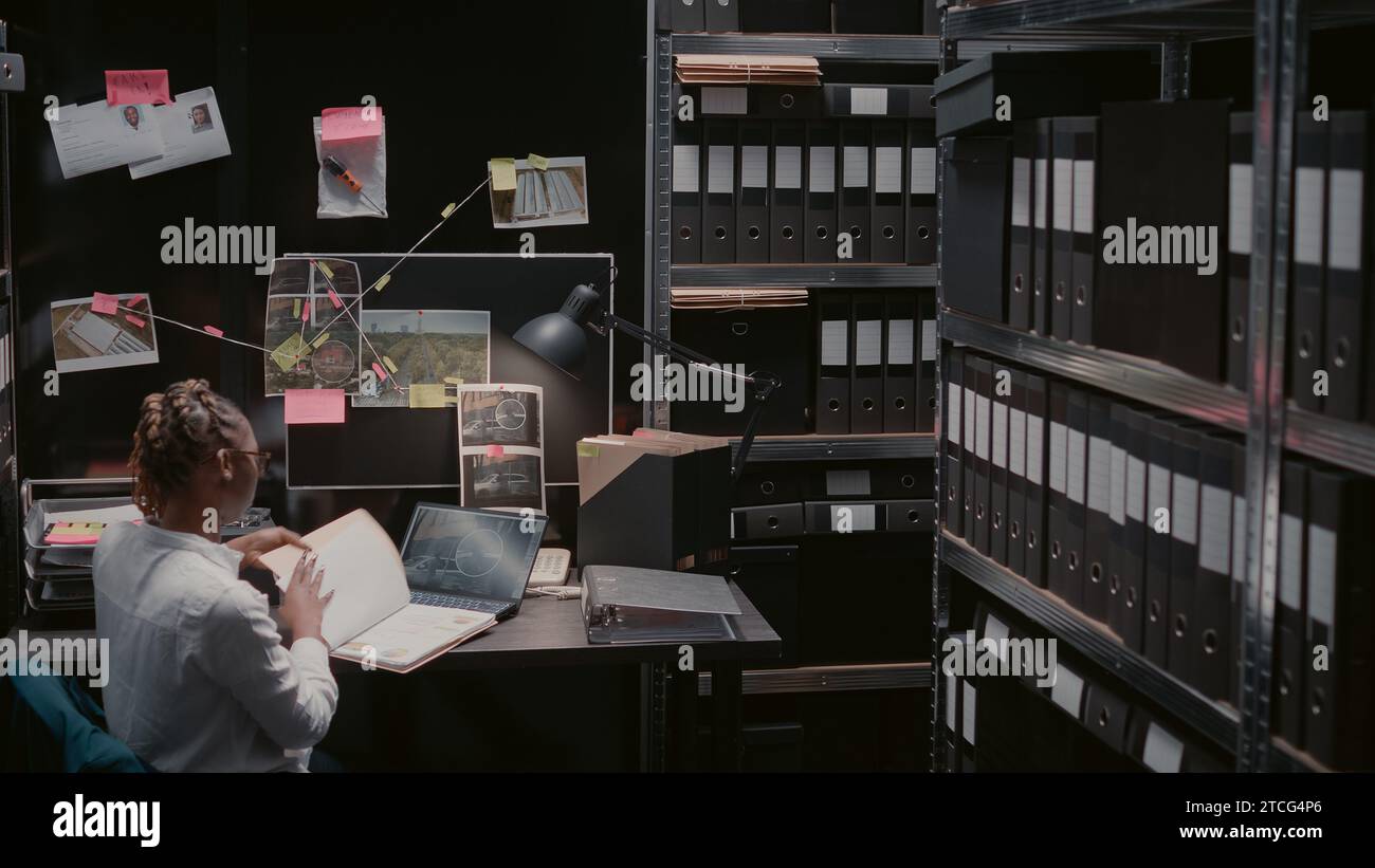 Law enforcement agent reading archive records at desk, conducting ...