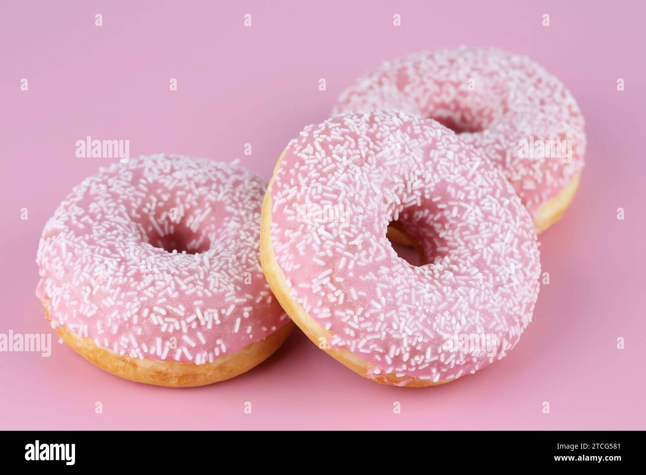 Three fresh donuts on pink background Stock Photo - Alamy
