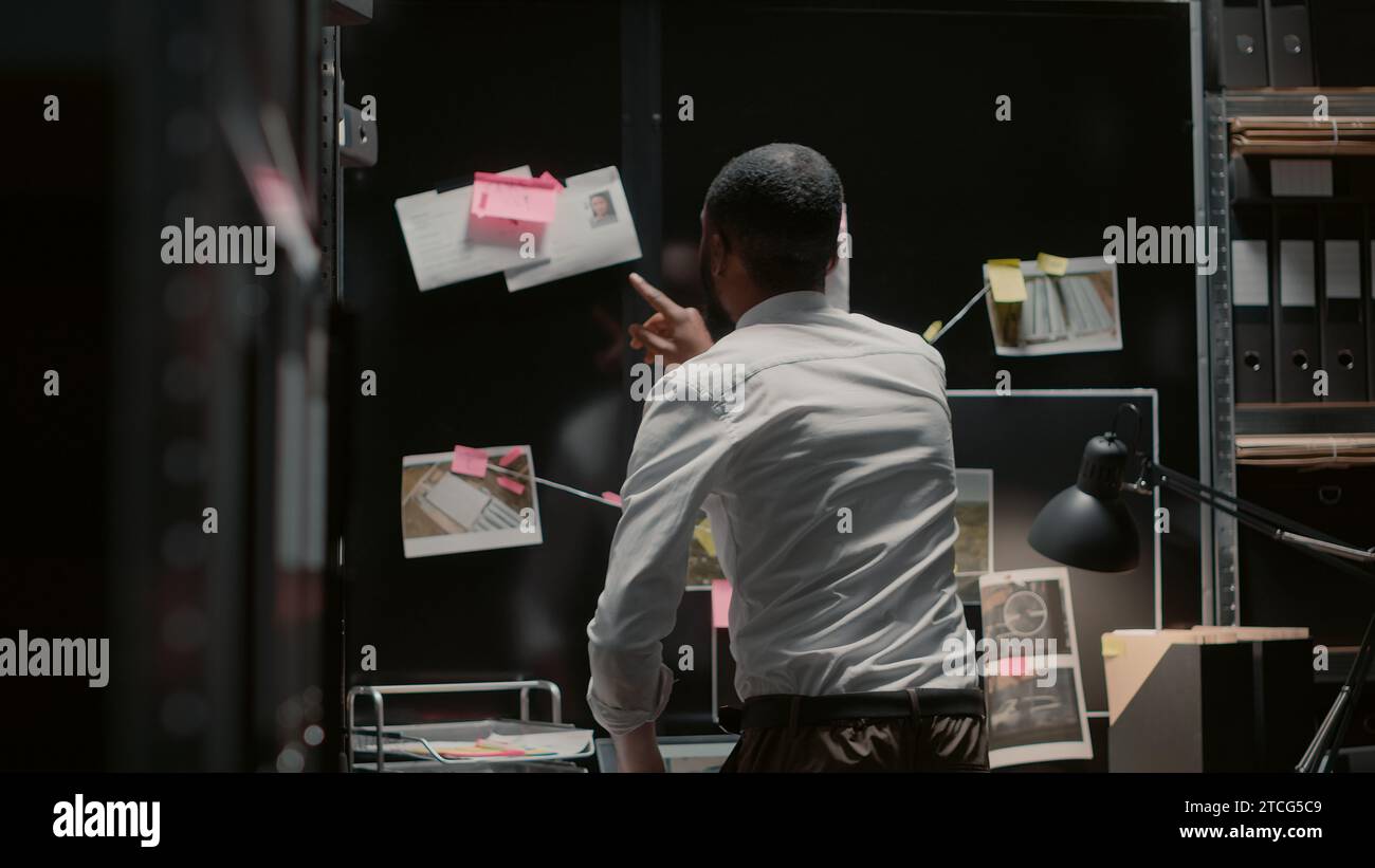 Professional police officer hanging clues on wall map to conduct ...