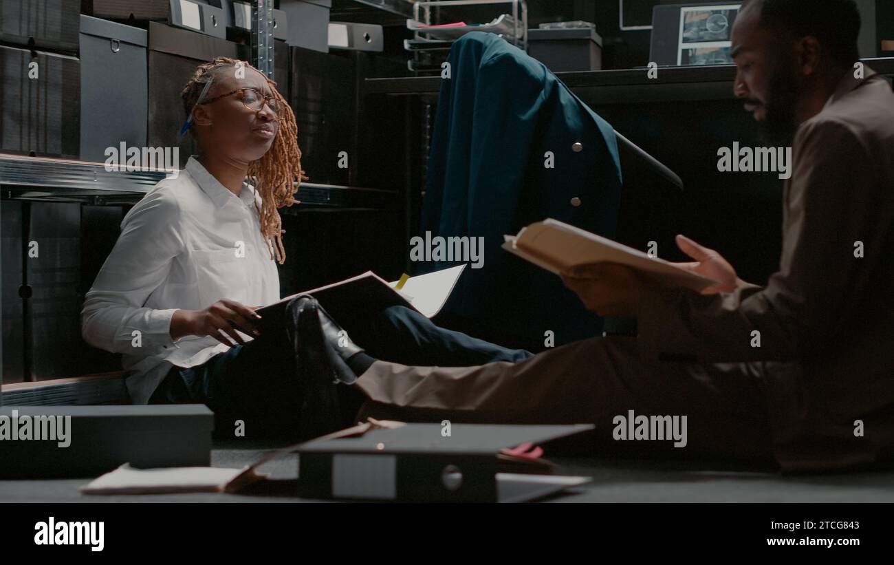 Police officers team examining case files records, sitting on the floor ...