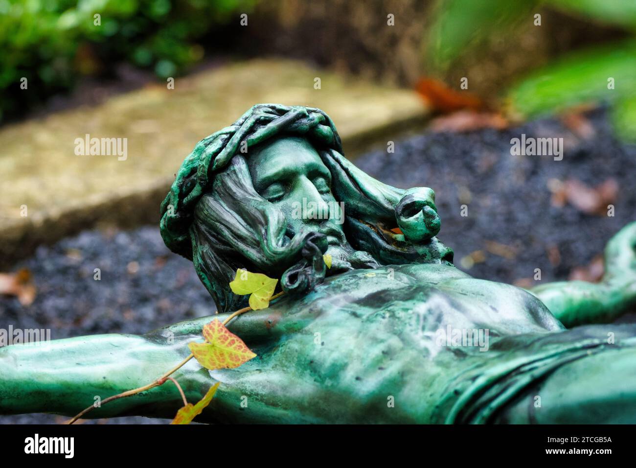 jesus fallen from the cross on the ground with ivy vines in a cemetery ...