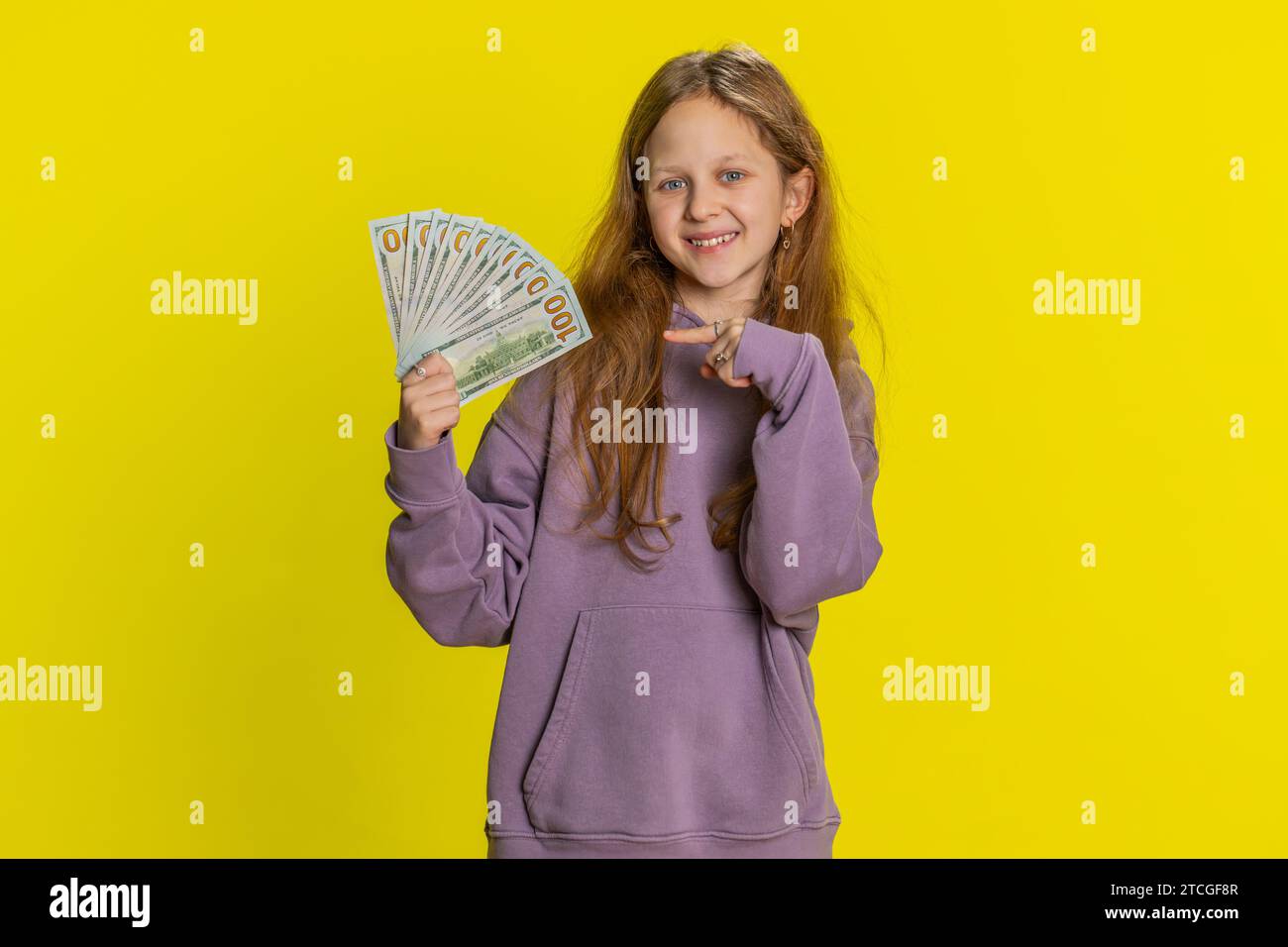 Portrait of rich pleased young cute school girl waving money dollar ...