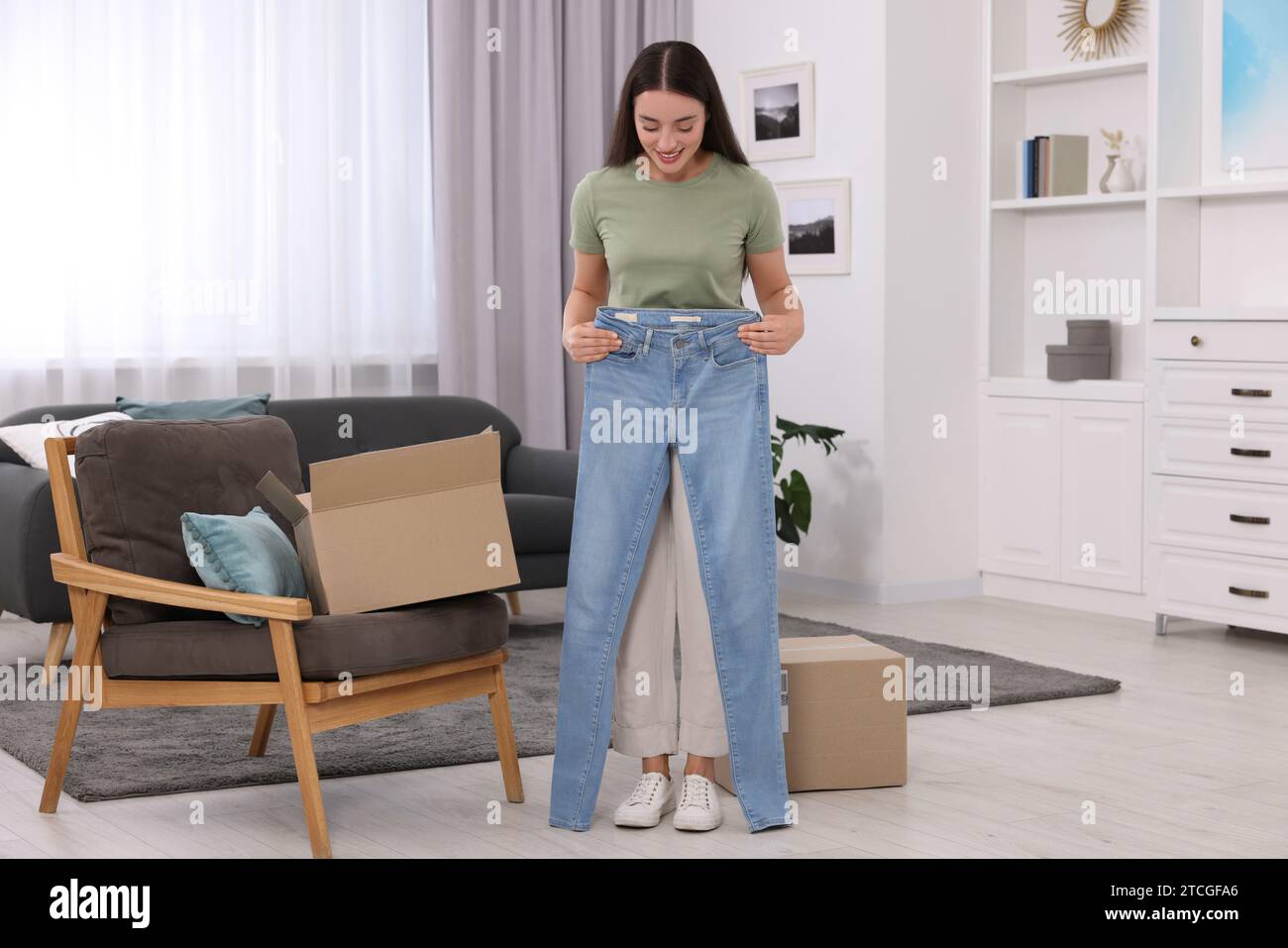 Happy woman with stylish light blue jeans at home. Online shopping ...