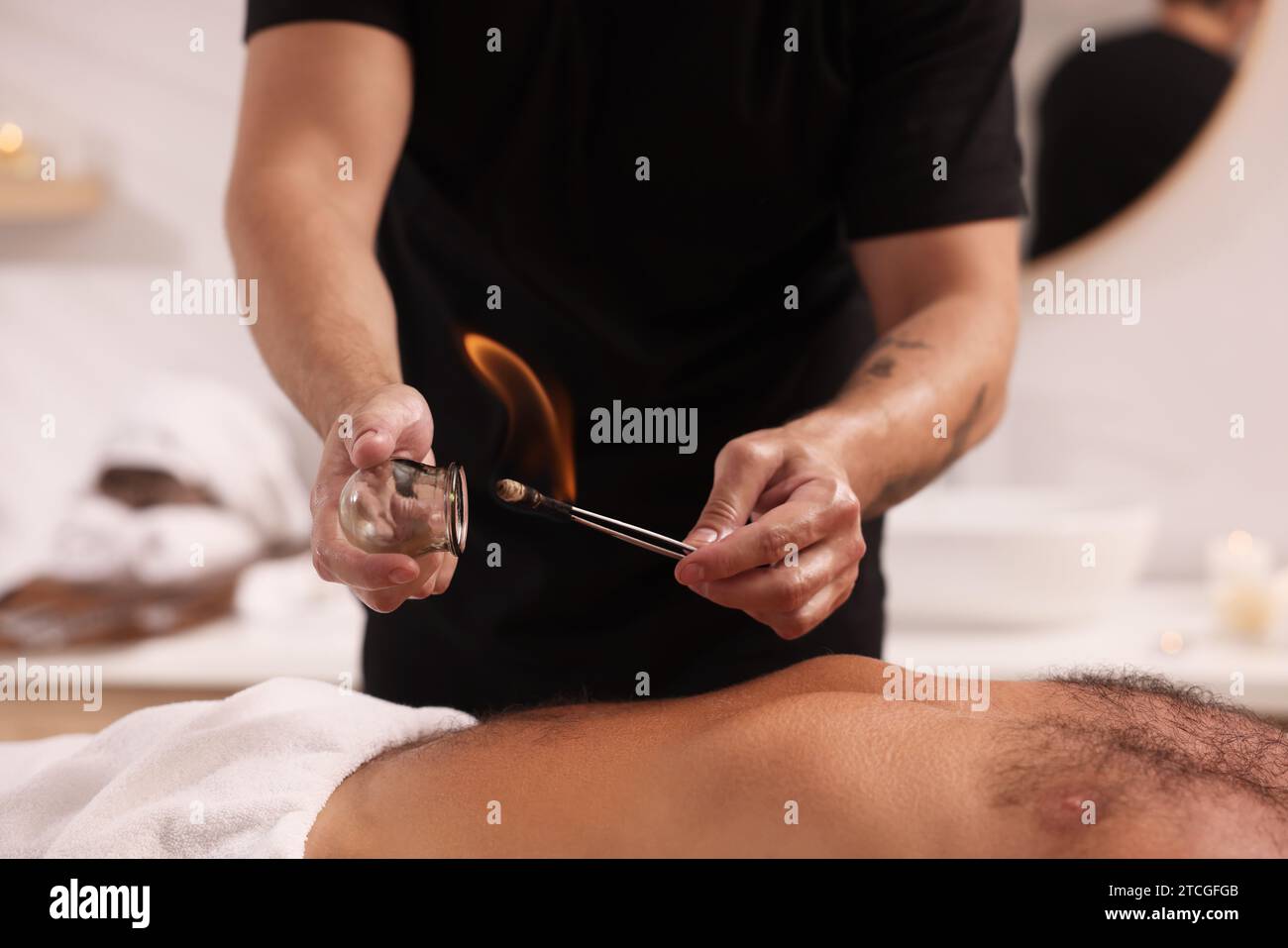 Therapist giving fire cupping treatment to patient indoors, closeup ...