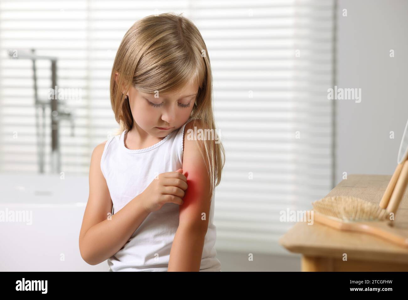 Suffering from allergy. Little girl scratching her arm in bathroom ...