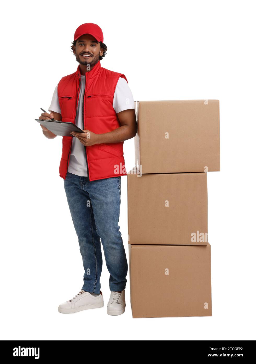 Happy young courier with stack of parcels and clipboard on white ...
