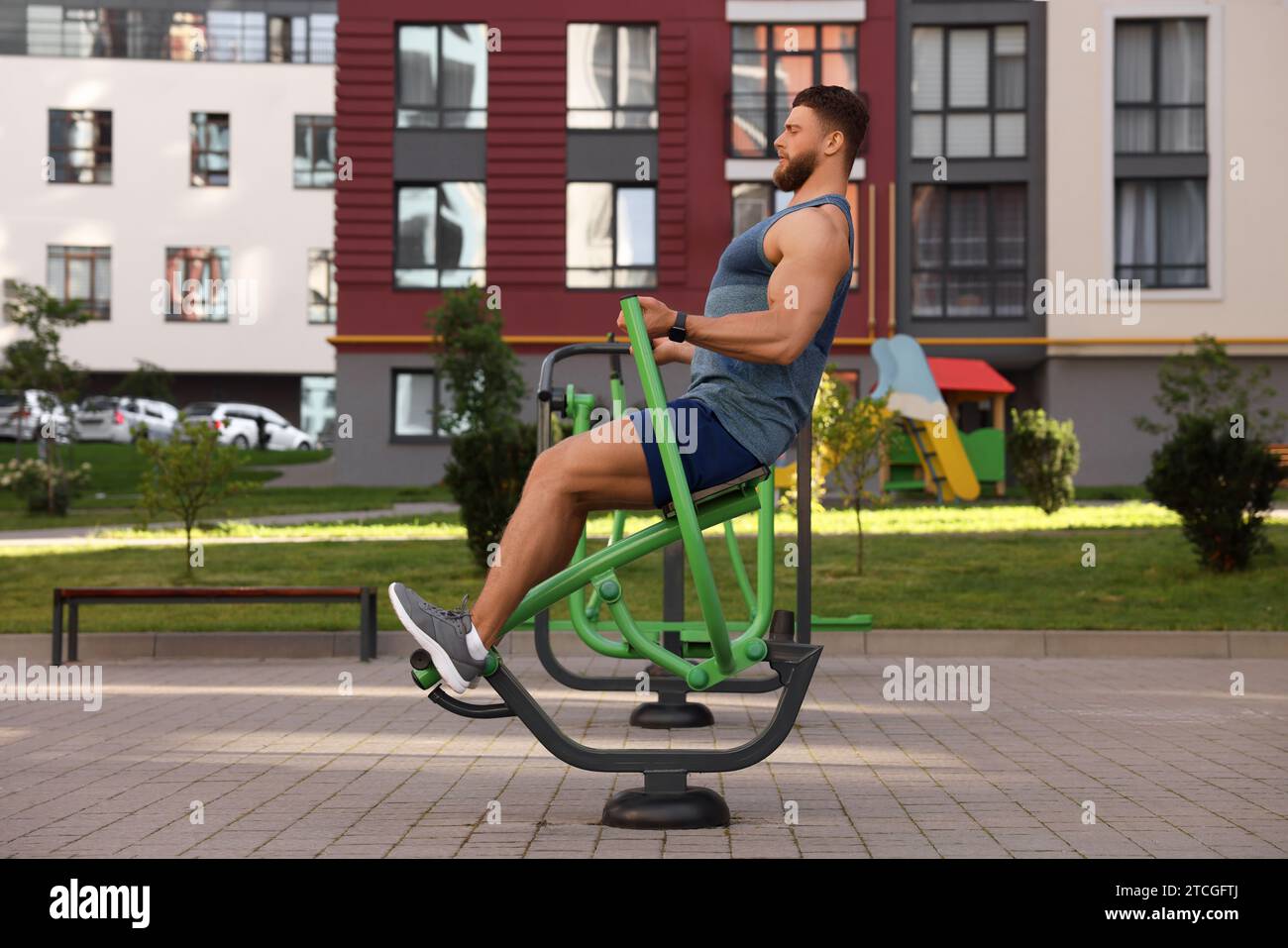Man training on rowing machine at outdoor gym Stock Photo - Alamy