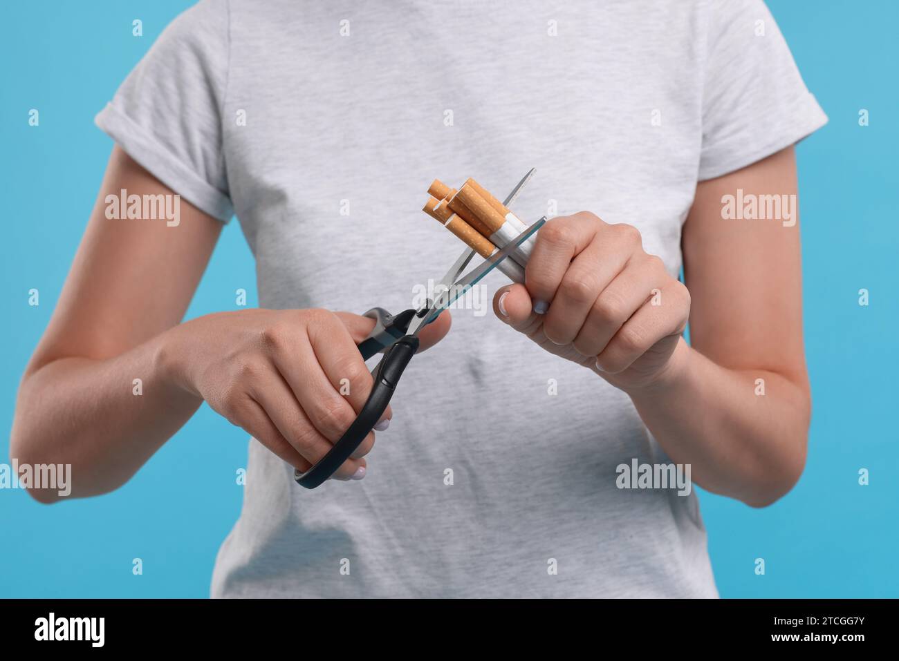 Stop smoking concept. Woman cutting cigarettes on light blue background ...