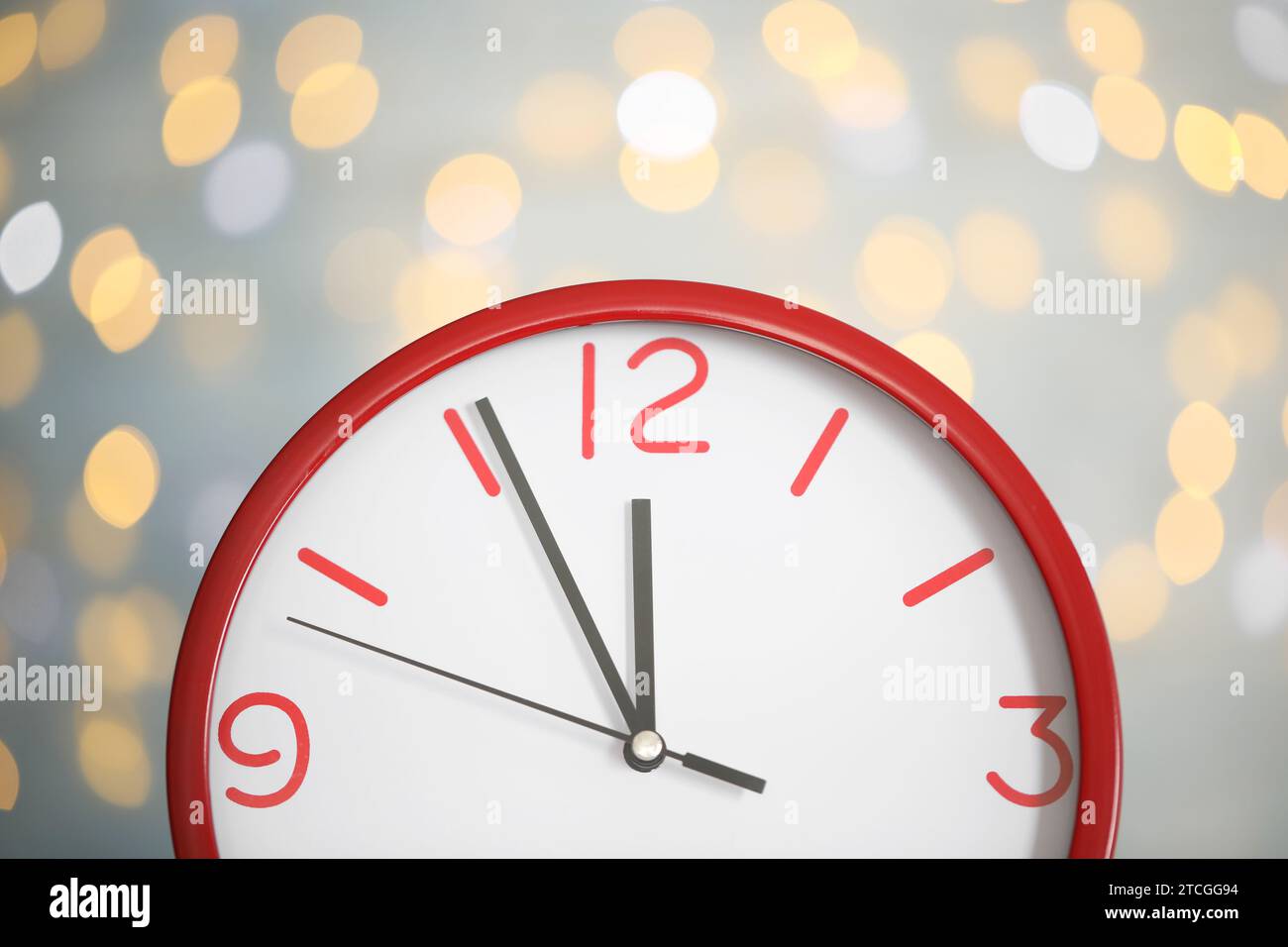 Clock showing five minutes until midnight on blurred background ...