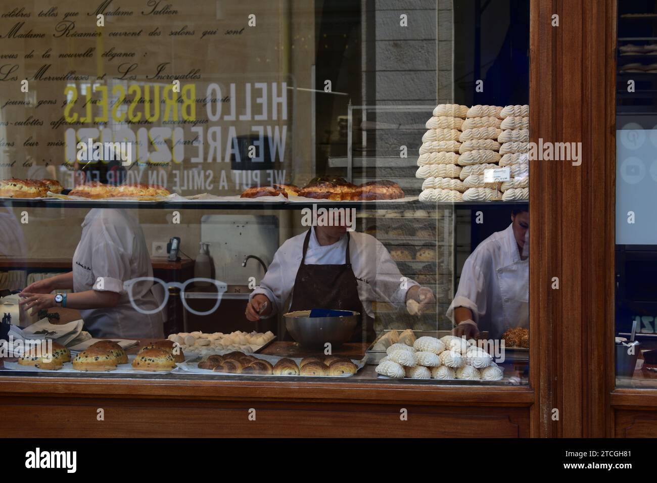 Female pastry chef making pastry goods behind storefront window at the ...