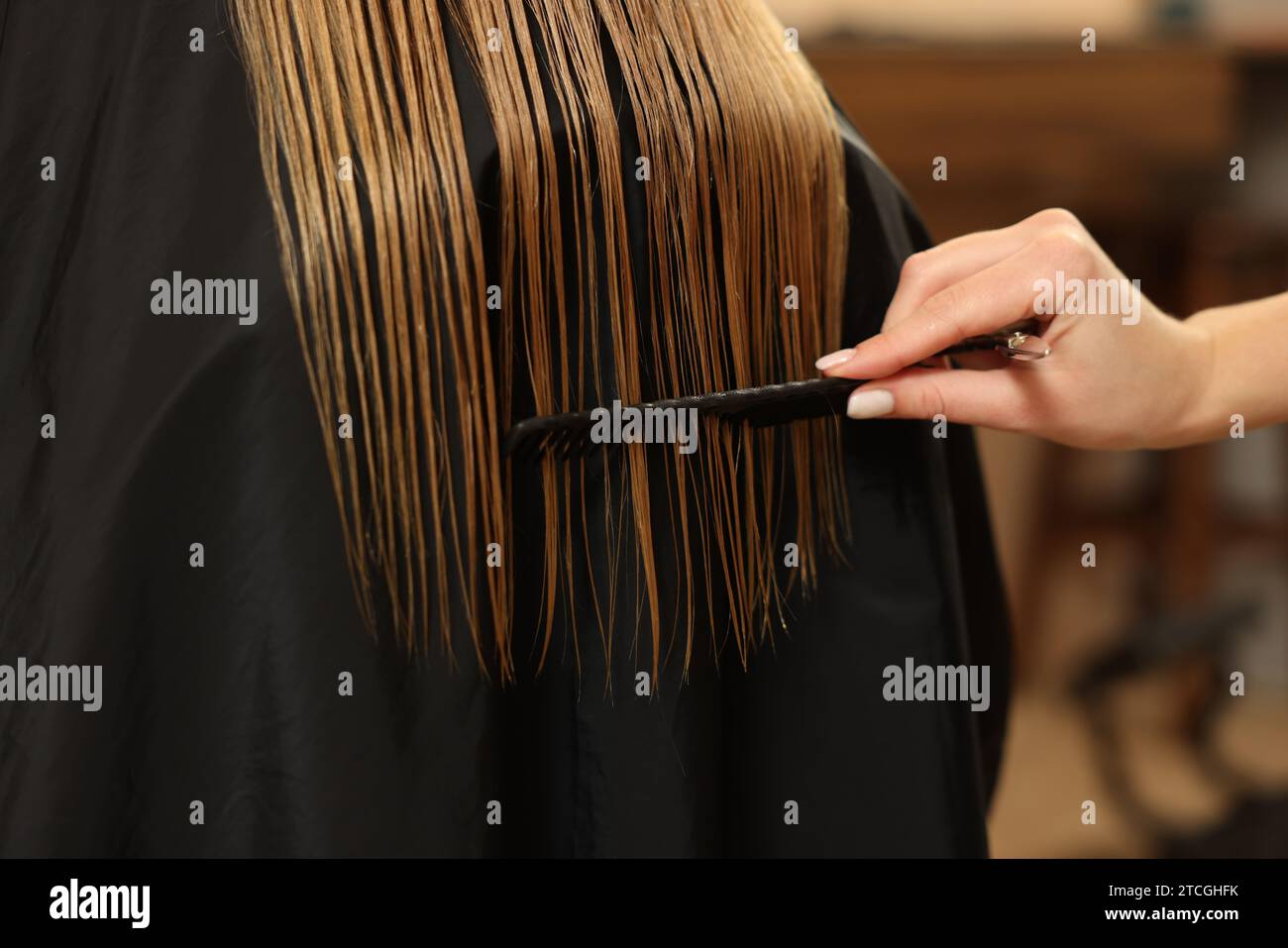 Professional hairdresser combing girl's hair in beauty salon, closeup ...