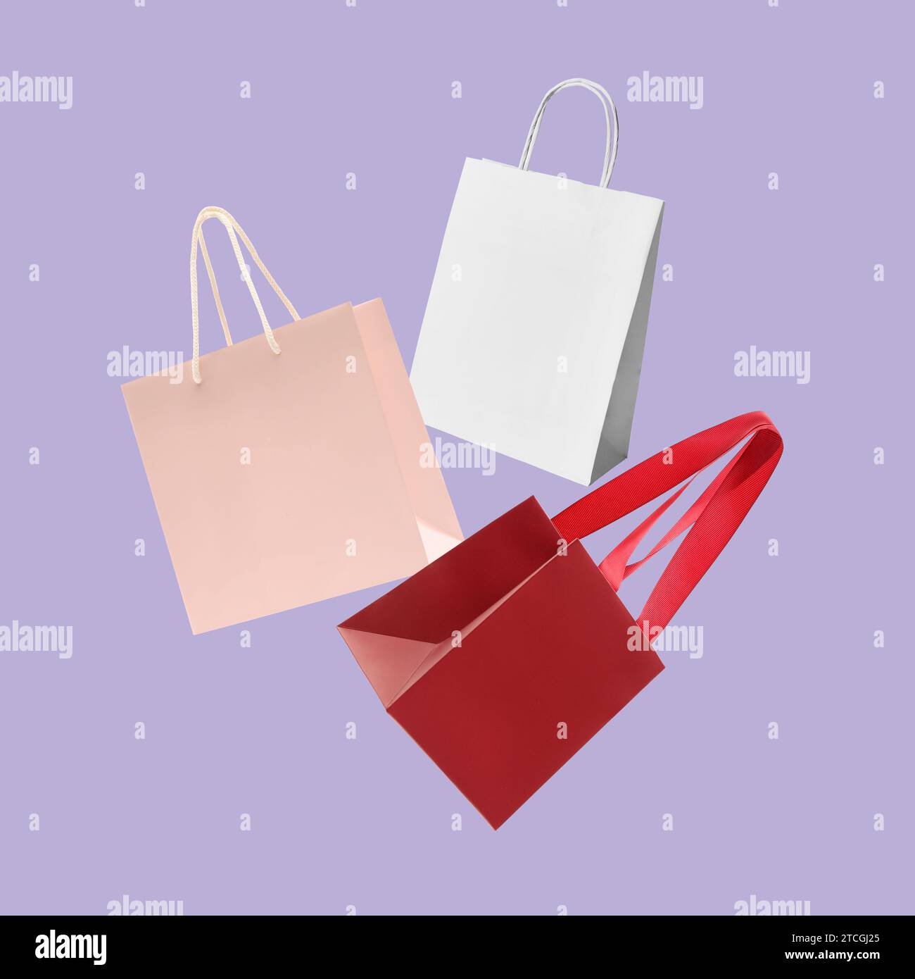 Colorful shopping bags falling on lilac background Stock Photo - Alamy