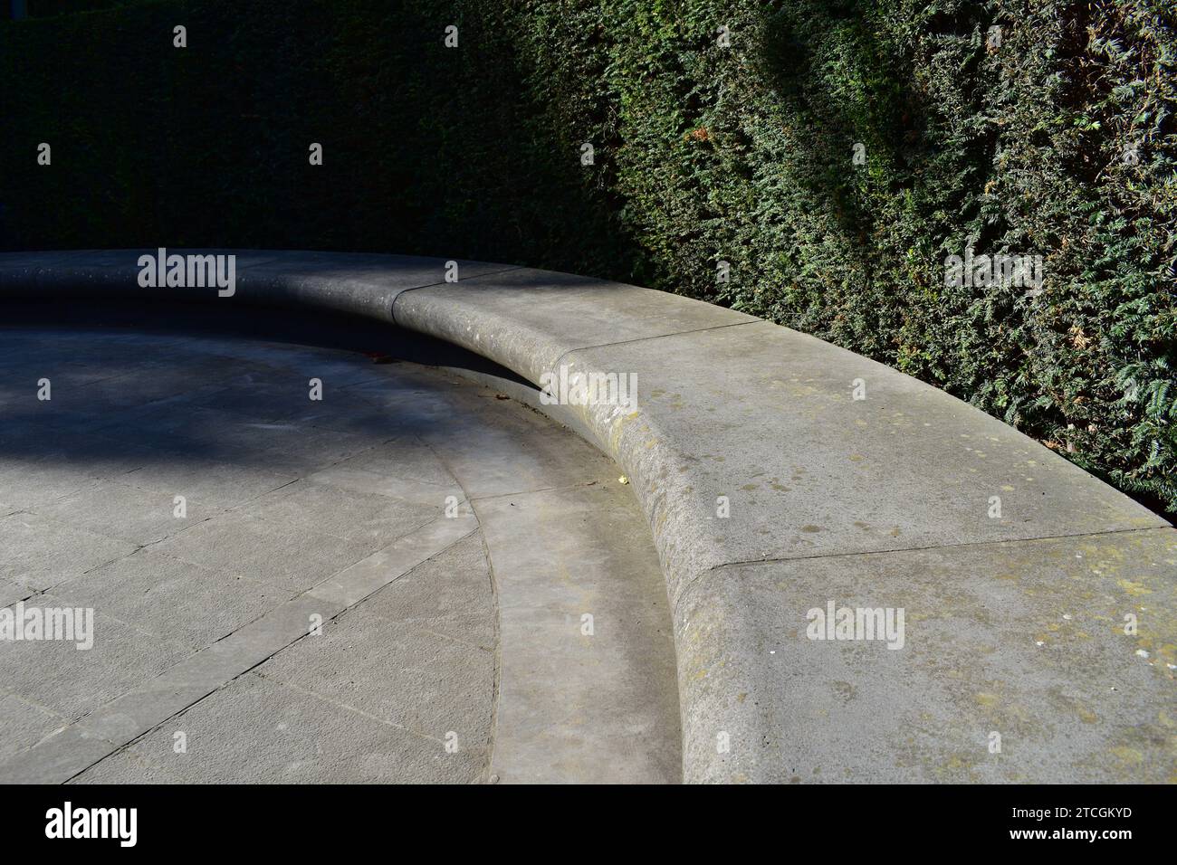 Circular stone sitting ledge with stone paved area on the inside and a ...