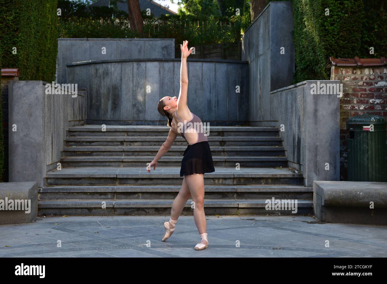 Young woman in purple top and black skirt performing a ballet pose on ...