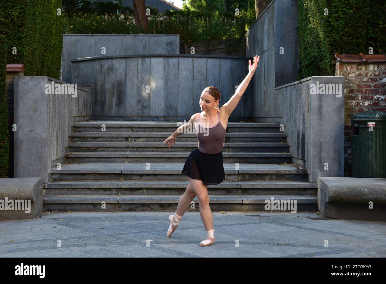 Young woman in purple top and black skirt performing a ballet pose on ...
