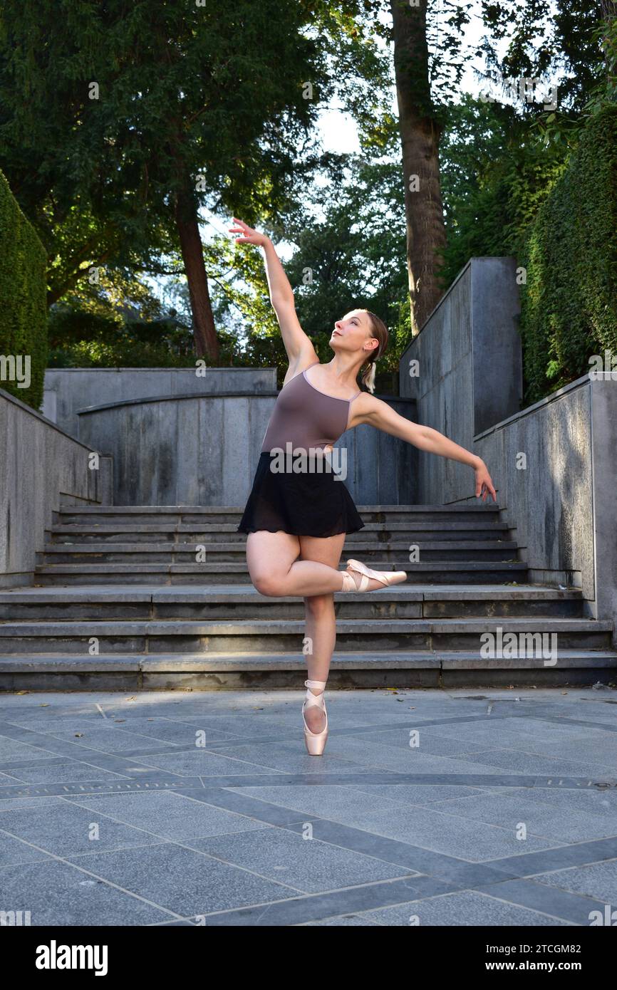Young woman in purple top and black skirt performing a ballet pose on ...