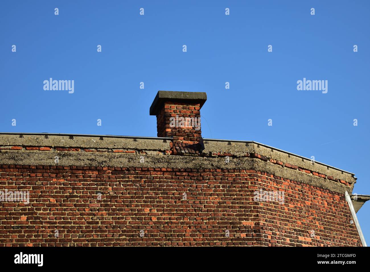 Small brick chimney on the edge of a roof on a brick building with blue ...