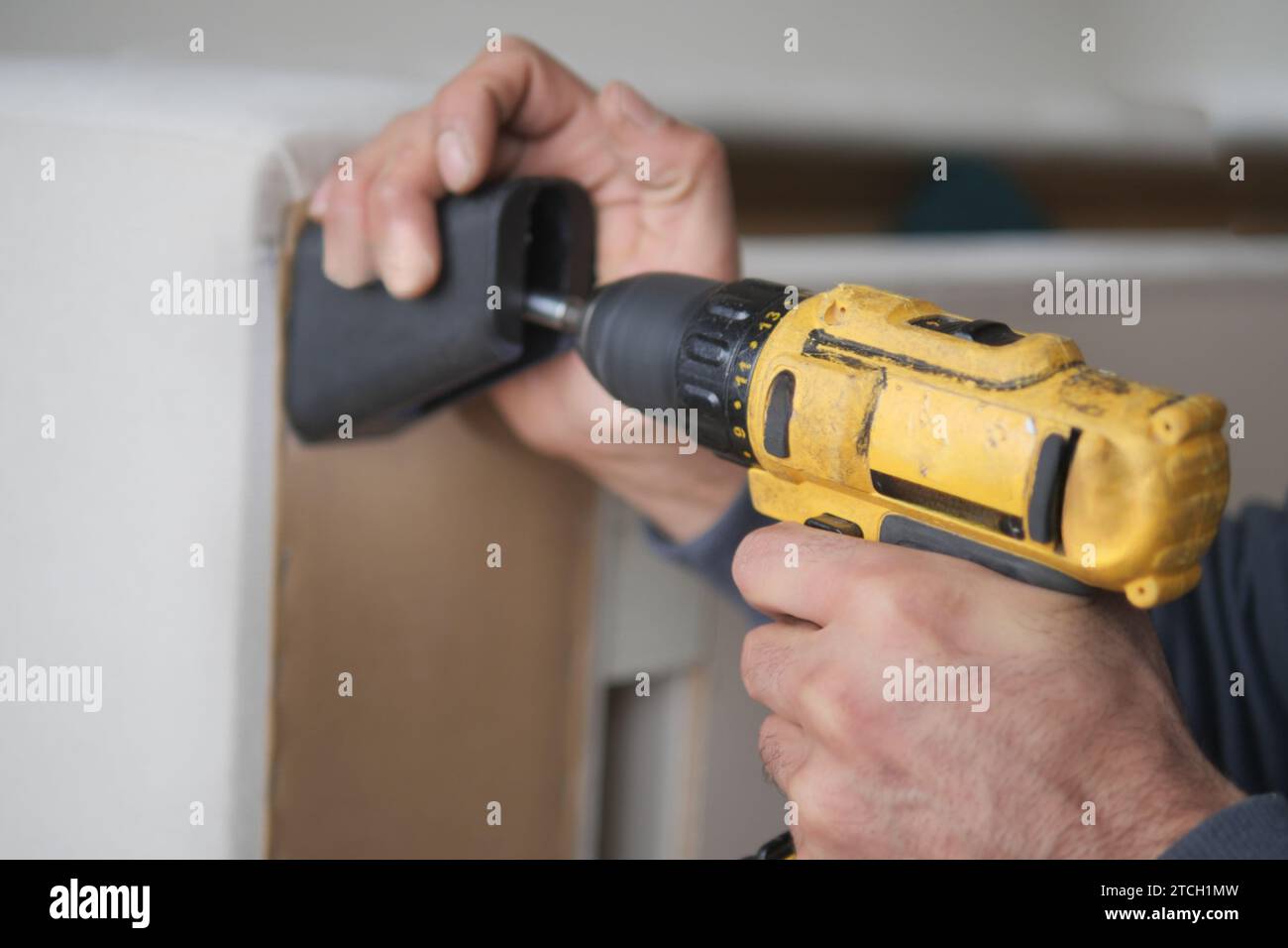 using electric drilling on fixing sofa Stock Photo - Alamy