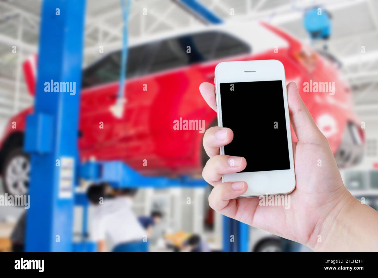 woman hand hold touch screen mobile smart phone with car garage ...