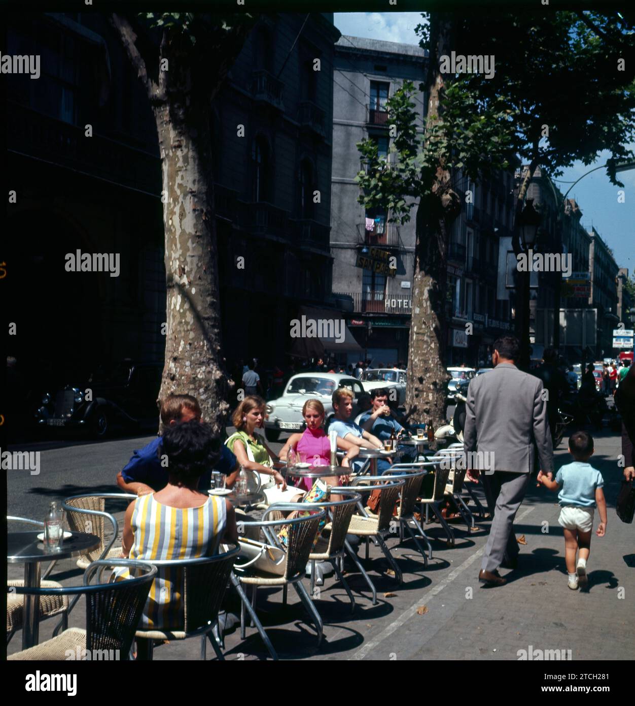 Barcelona, June 1966. A child walks holding his father's hand next to a terrace on Las Ramblas ...
