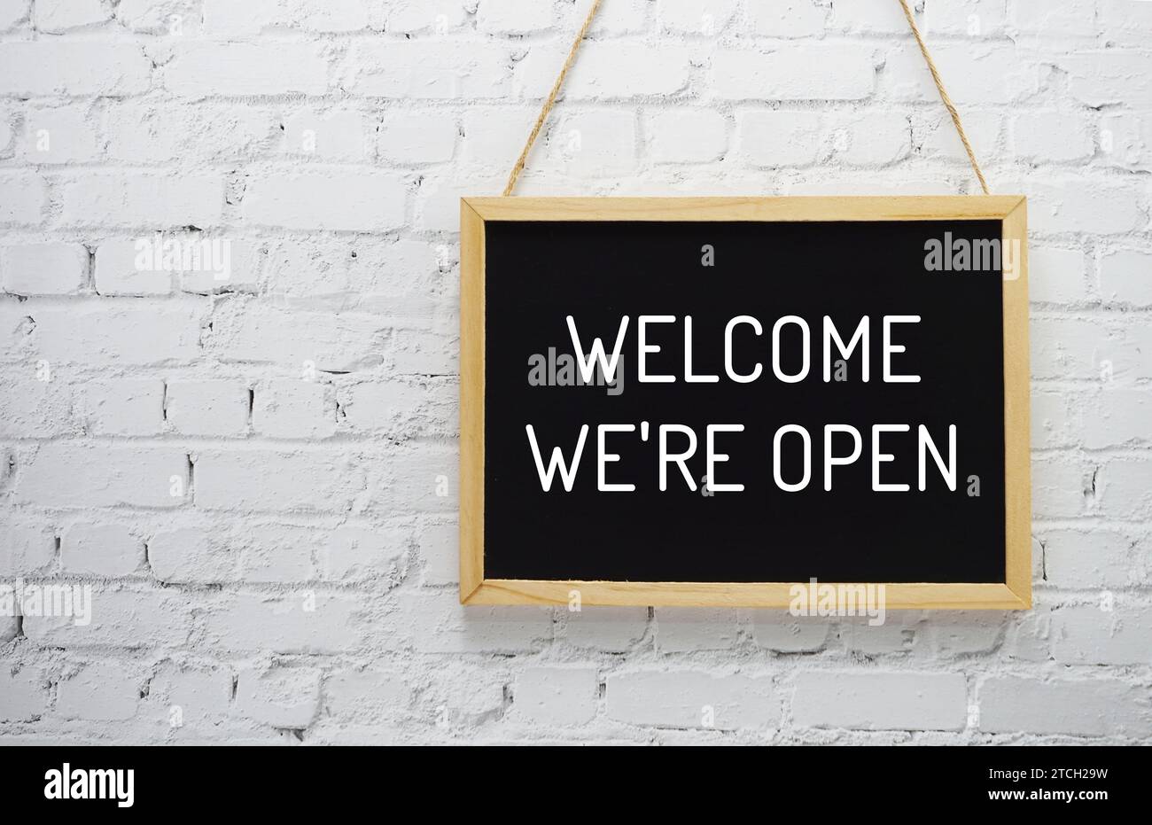 Welcome We are Open typography text on blackboard hanging against on ...