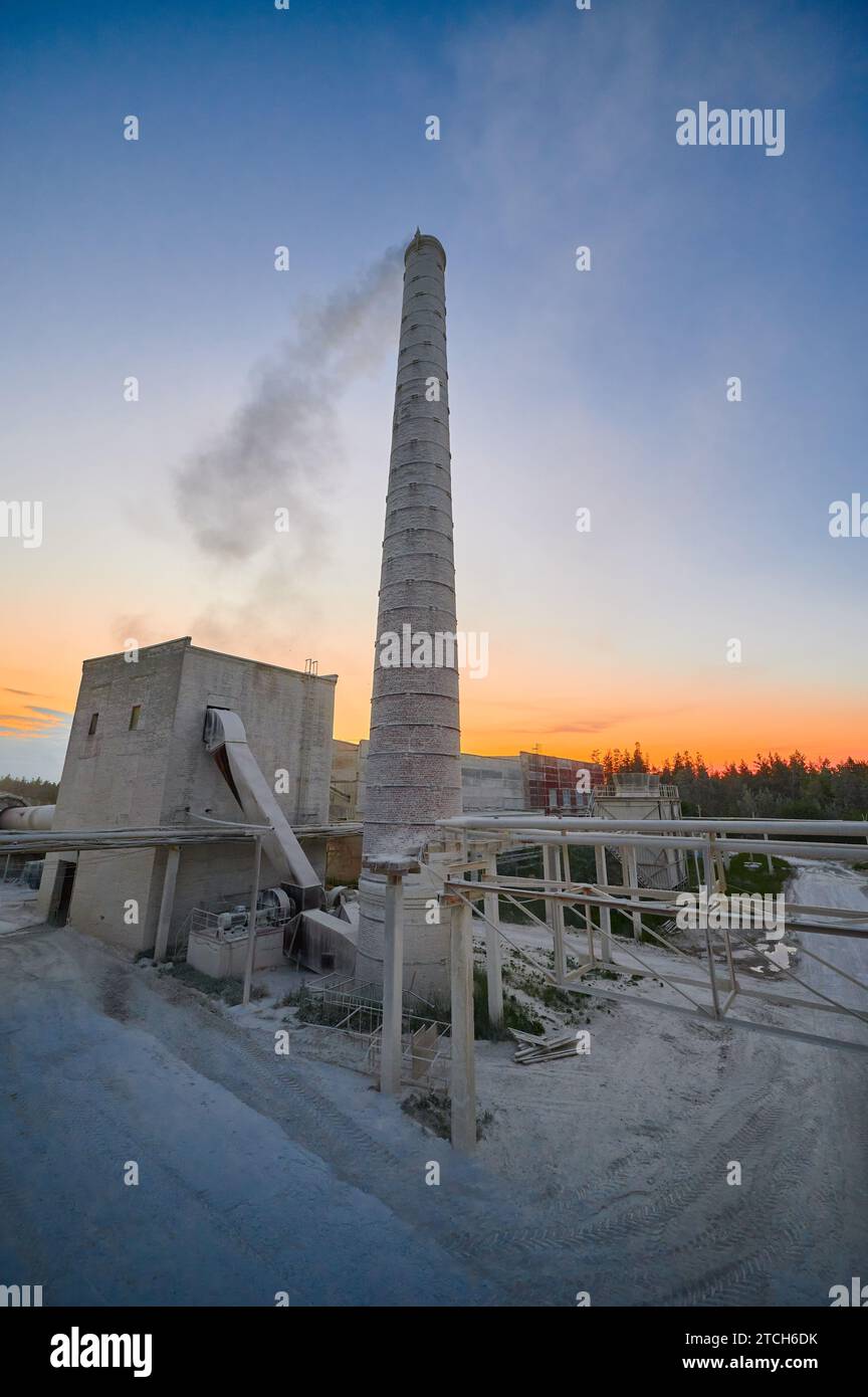 High smoking pipe at limestone production plant in evening Stock Photo ...