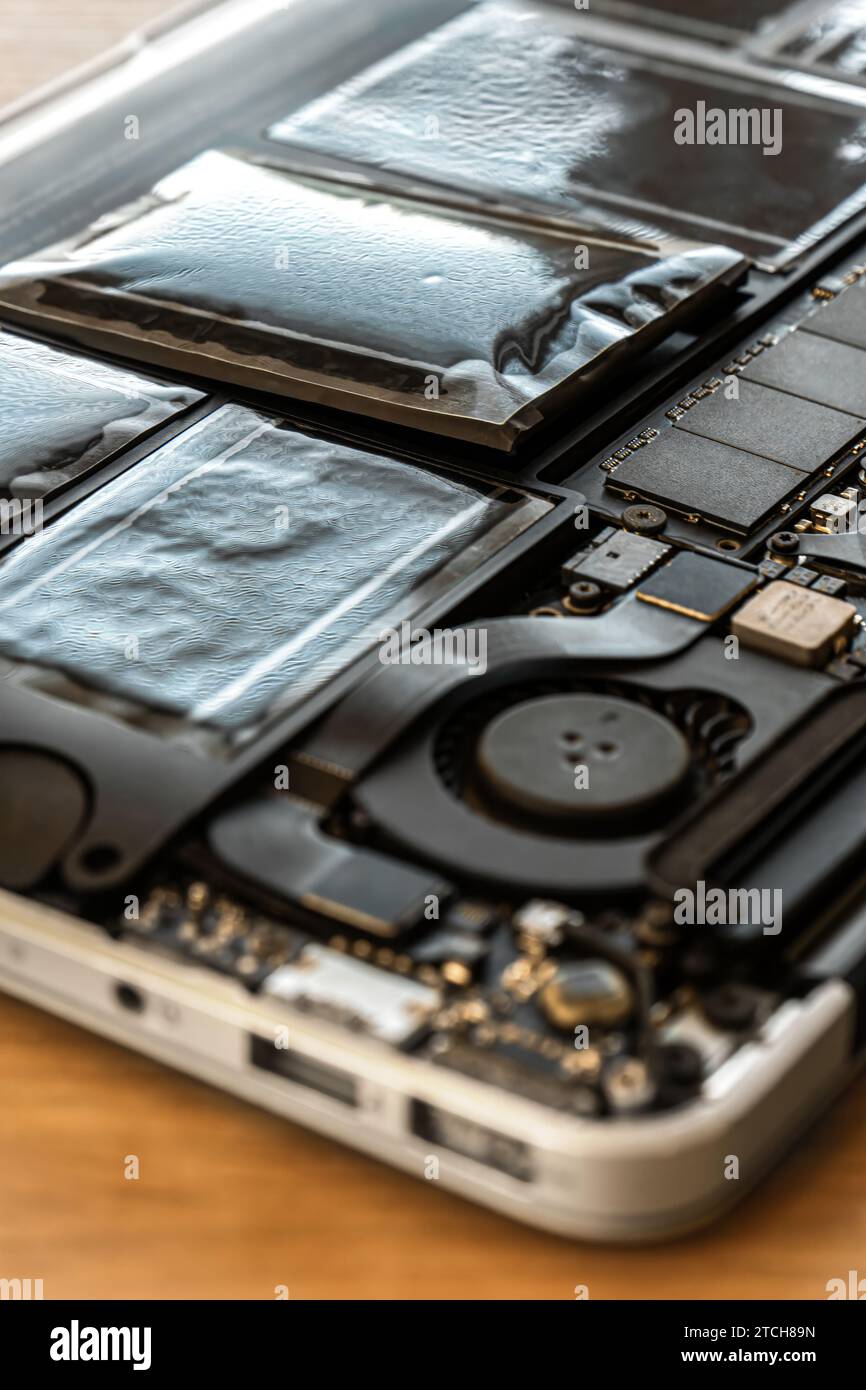 Swollen battery of broken laptop in open casing closeup. Heavy damage ...