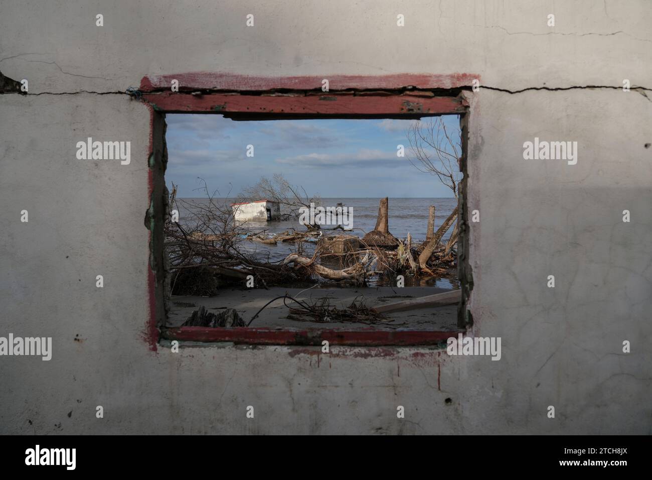 A window frames a portion of the shore littered with debris left from ...