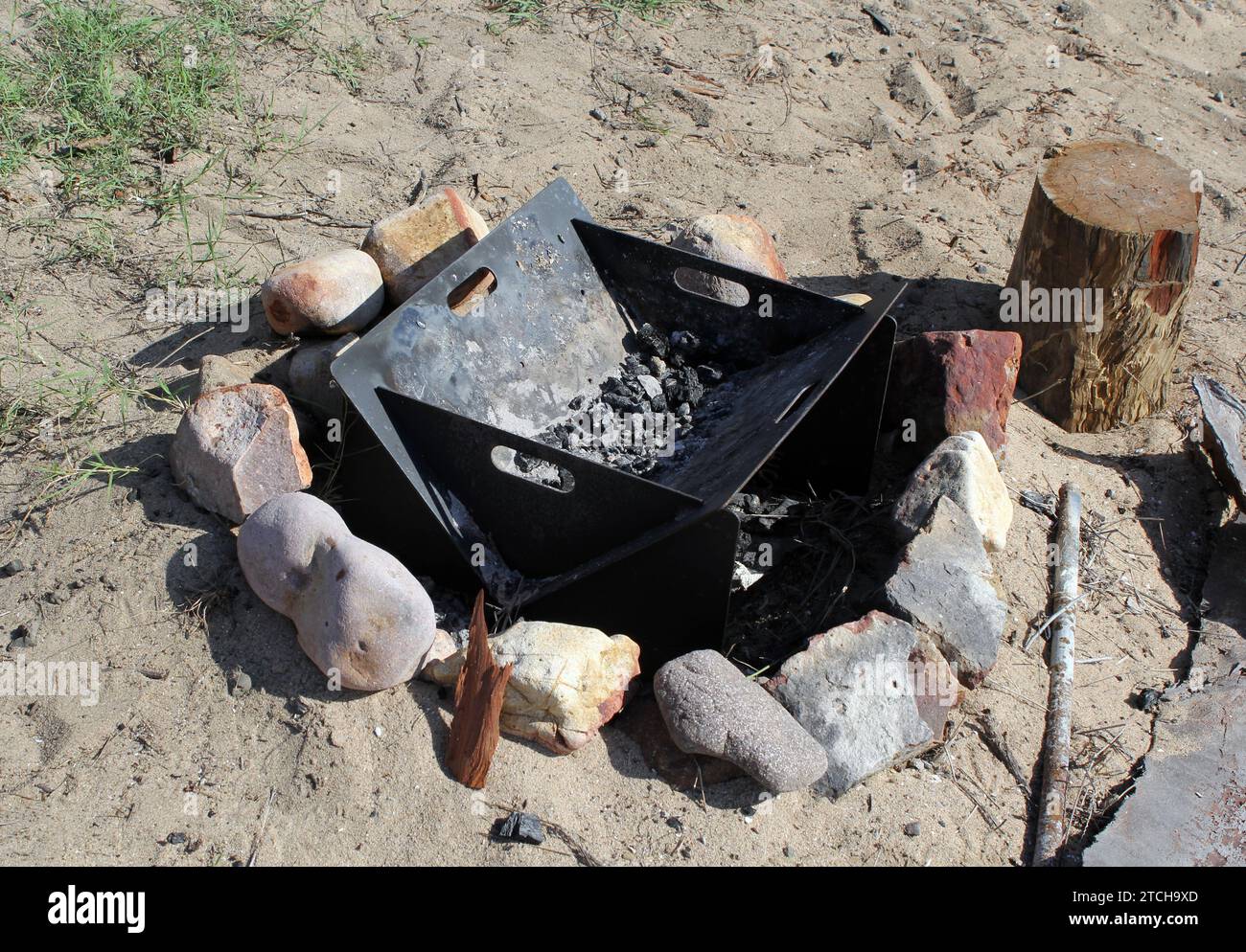 Fire pit with charcoal and stones on a beach with sand Stock Photo - Alamy