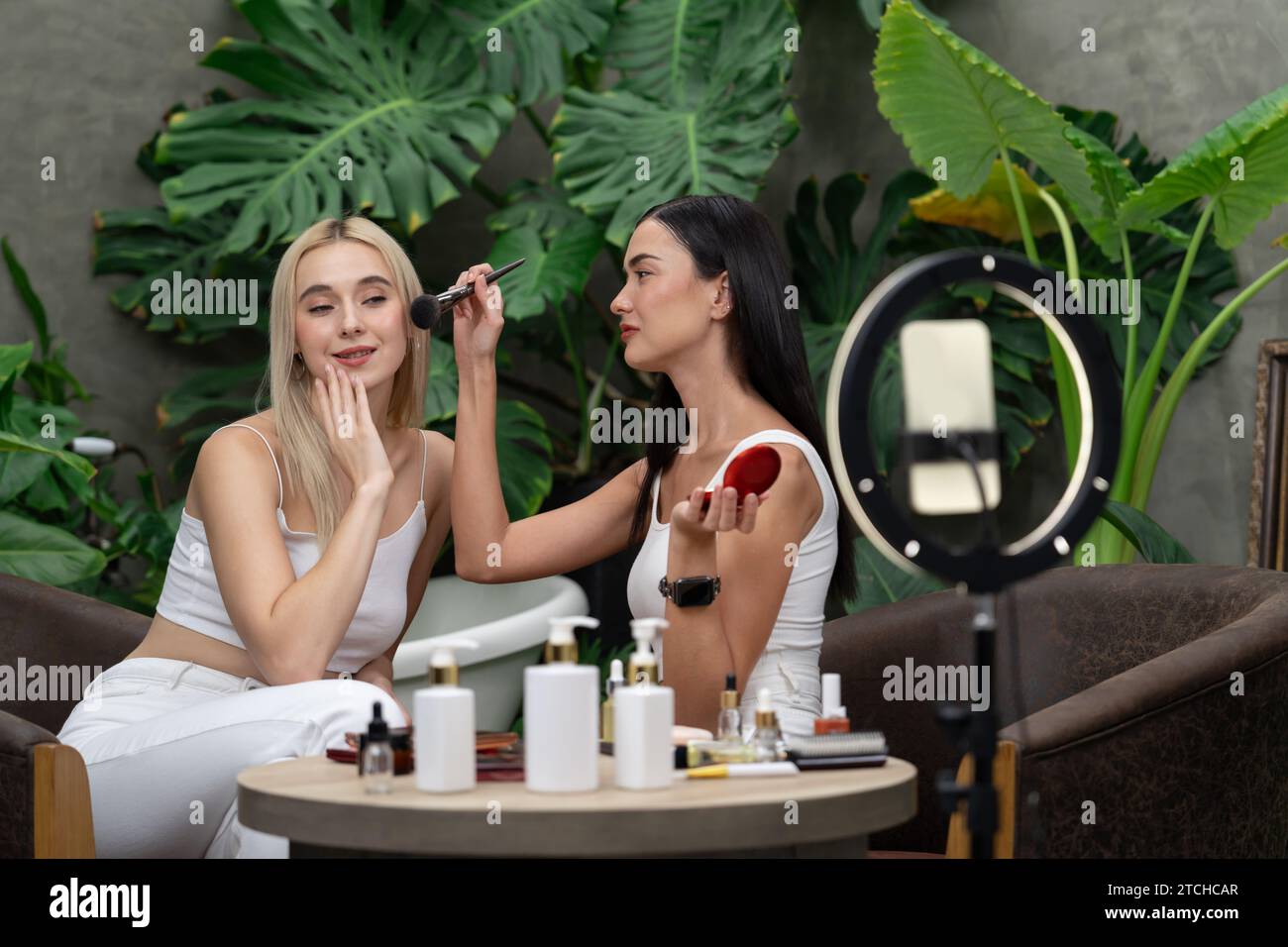 Two beautiful content creator making natural beauty and cosmetic tutorial on green plant garden ...