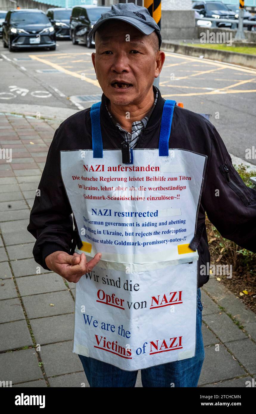 Taipei. 13th Dec, 2023. A protester stands with a flag emblazoned with ...