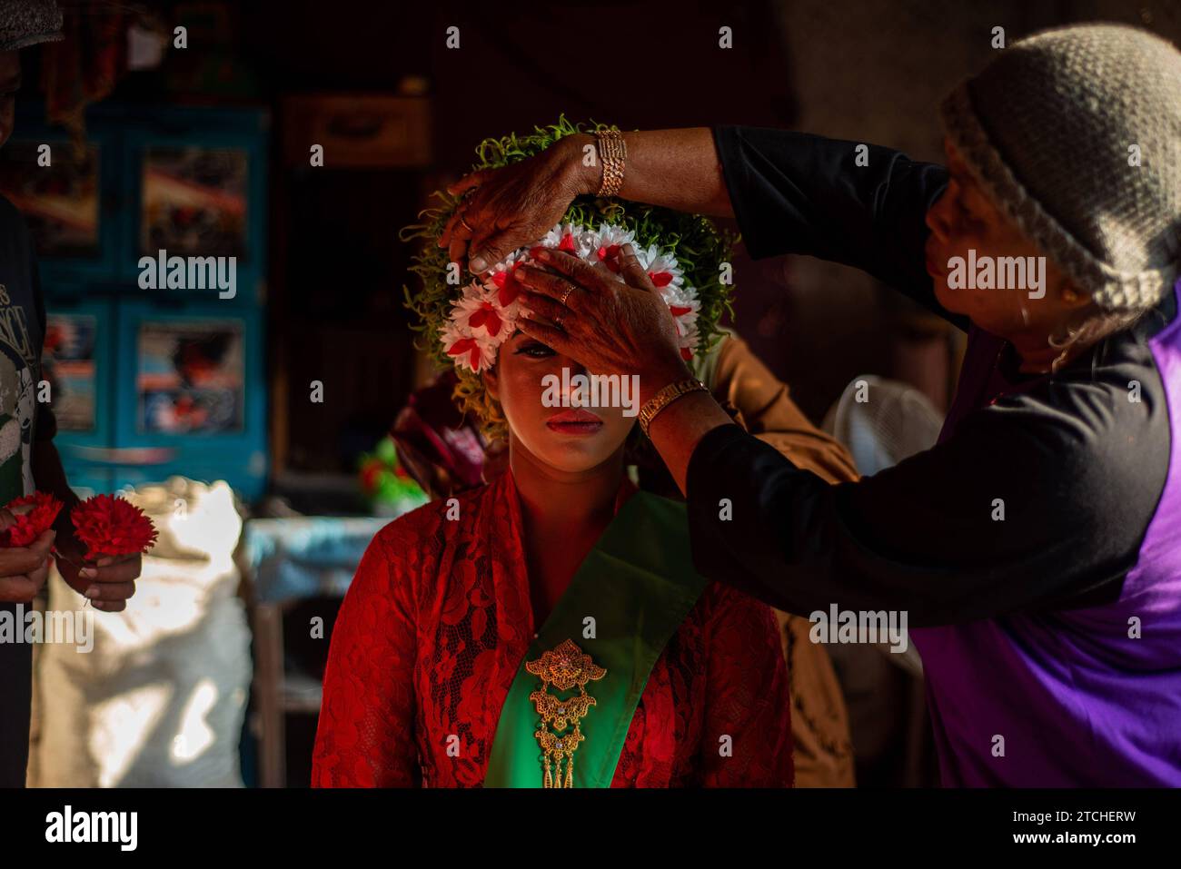NGAROT FESTIVAL A girl prepares a flower decoration on her head while ...
