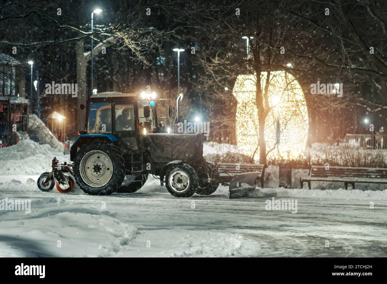 A snow plow tractor clears a snowy road in public park after severe ...