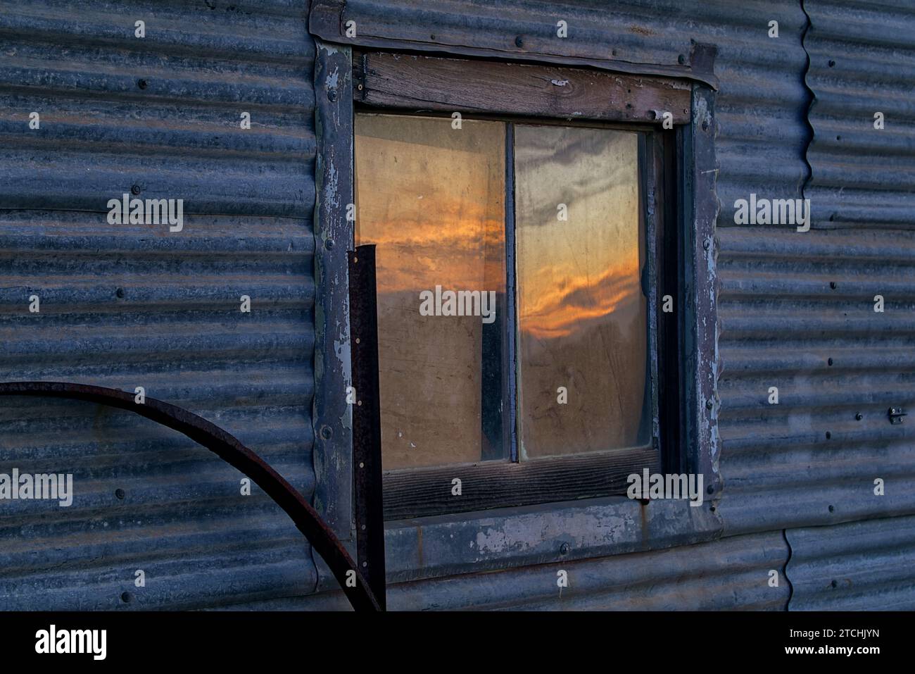 Sunset reflection in the windows of a corrugated farm out building ...