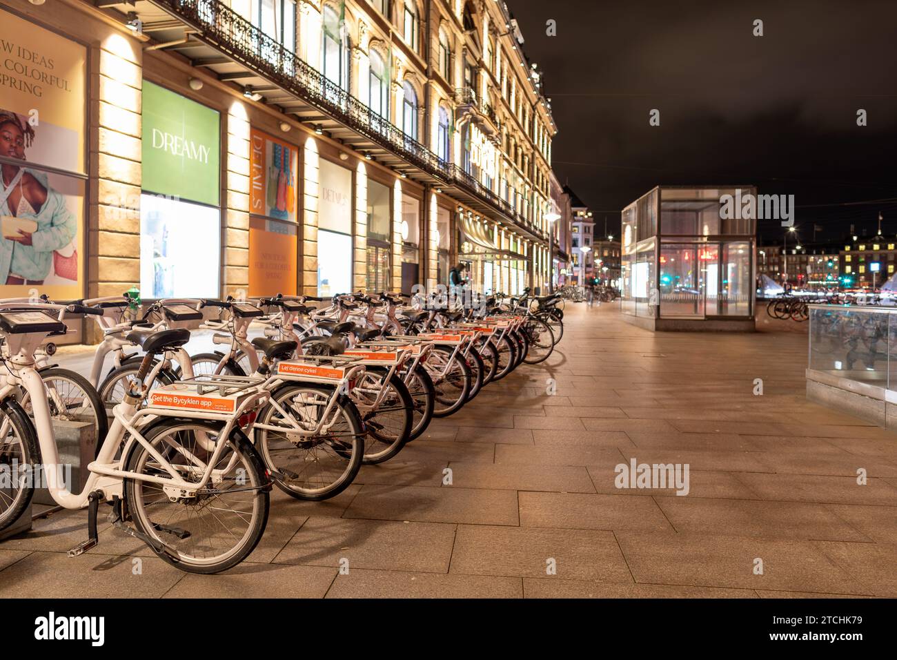 An outdoor view of an urban setting featuring a line of bicycles parked ...