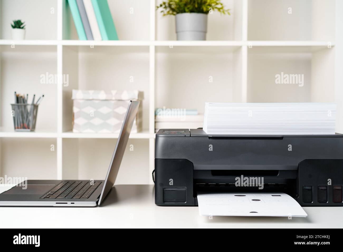 Modern printer with paper and laptop on table in office Stock Photo - Alamy