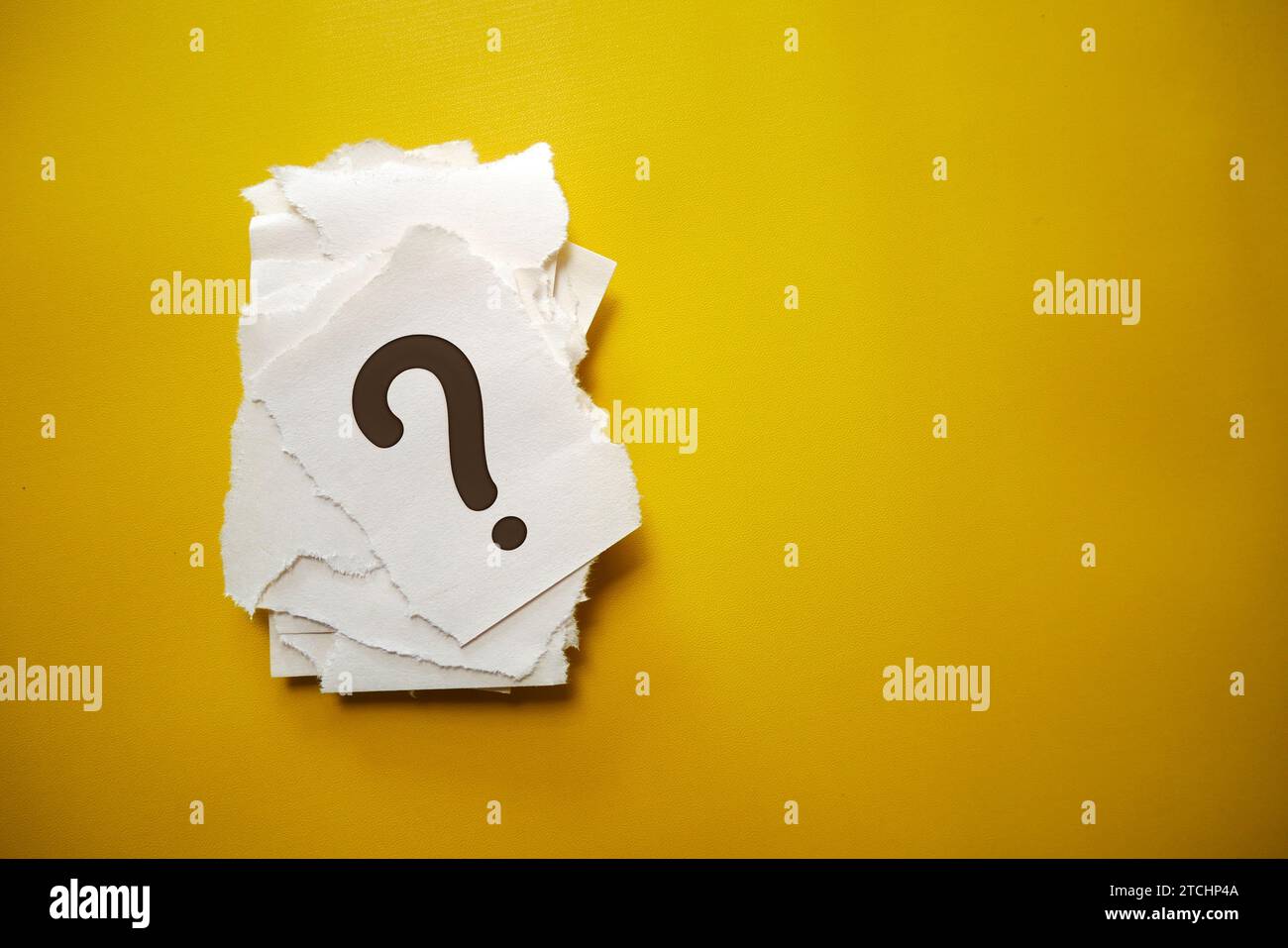 Torn paper showing question mark symbol on yellow background with copy ...